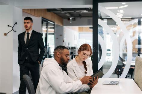 Two Colleagues Collaborating In A Modern Office While Discussing A