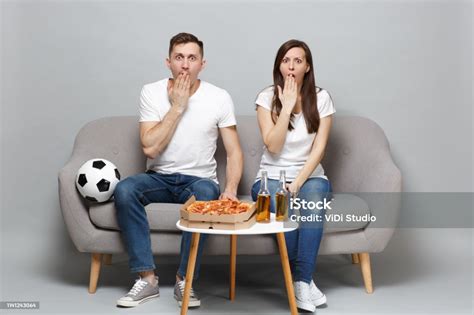 흰색 T 셔츠에 충격 커플 여자 남자 축구 팬 응원은 회색 배경에 고립 된 손바닥으로 무를 덮고 좋아하는 팀 지원 사람들의 감정 스포츠 가족 레저 라이프 스타일 개념입니다