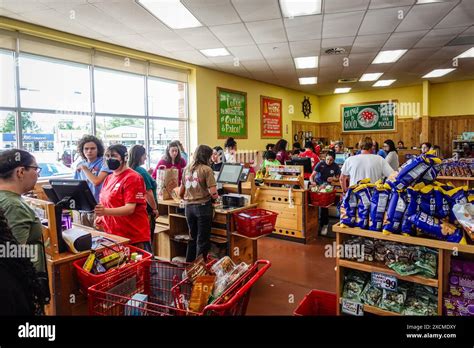 Crowded scene inside Trader Joe's supermarket with numerous people waiting in a long checkout ...