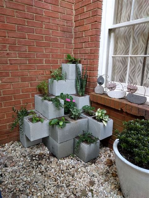 Several Cement Blocks With Plants Growing Out Of Them In Front Of A Brick Wall Next To A Window