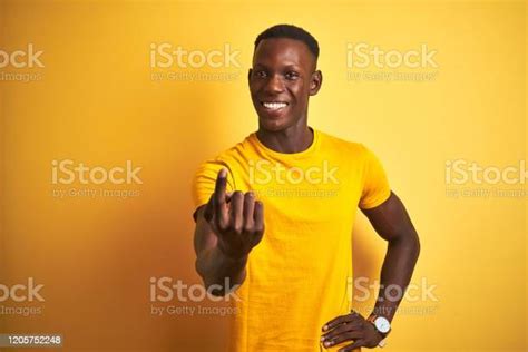 고립 된 노란색 배경 Beckoning 위에 서 캐주얼 티셔츠를 입고 젊은 아프리카 계 미국인 남자 는 행복하고 미소를 환영 하는 손을 함께 여기에 제스처 T 셔츠에 대한