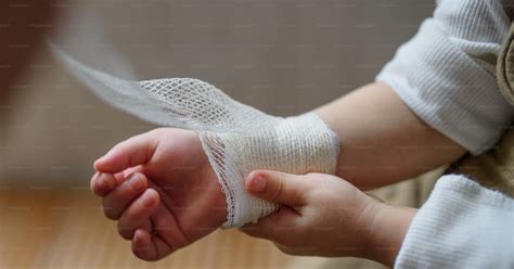 알아볼 수 없는 손이 집에서 실내에 붕대를 감고 있는 어린 아이를 다치게 합니다 사진 Unsplash의 붕대 이미지