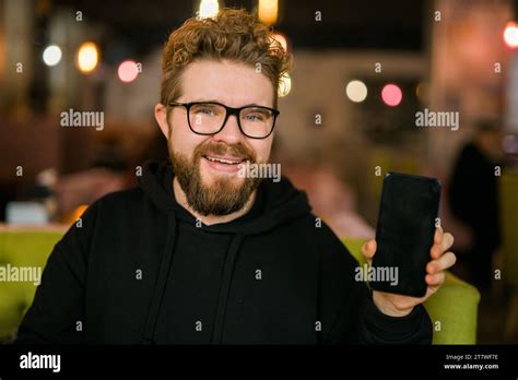 Satisfied Man With Dark Beard Holding Smartphone And Showing His Favorite Mobile App Male
