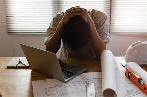 젊은 아시아 엔지니어 건축가 계약자 생각 하 고 건설 현장 계약자 개념에서 센터는 사무실 책상에 노트북 및 백색 안전 헬멧 새로운 프로젝트 계약 계획에 대 한 걱정 건설