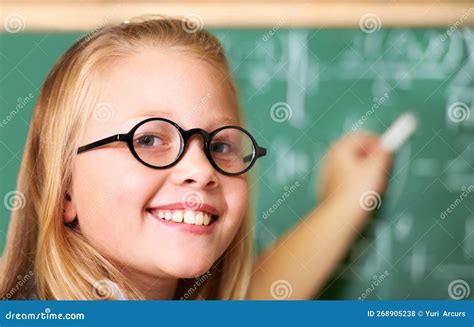 Showing Her Classmates How Its Done Portrait Of A Cute Blonde Girl Using Chalk In Class Stock