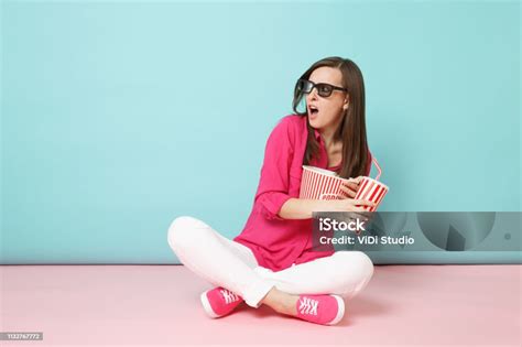 장미 셔츠 밝은 분홍색 파란 파스텔 벽 배경 스튜디오에 고립 된 영화 필름을 보고 바닥에 앉아 흰색 바지에 전체 길이 초상화 재미 있는 여자 패션 라이프 스타일 개념입니다