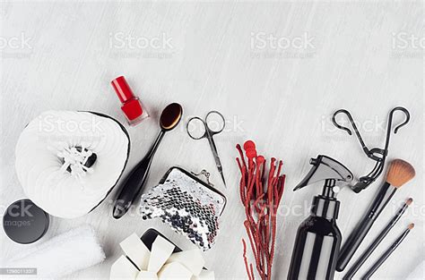 고급 블랙 메이크업 액세서리 얼굴 관리를위한 화장품 제품 부드러운 밝은 흰색 나무 보드 상단 보기 테두리에 빨간색 나뭇 가지와 매니큐어와 피부 클렌저 0명에 대한 스톡 사진