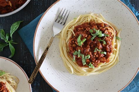 살코기 파스타 풍부한 토마토 소스 양파 마늘 바질 잎 장식의 수제 볼로네즈 소스를 얹은 스파게티 파스타의 이미지 볼로네즈 소스를 함유한 금속 그릇 옆에 흰색 접시에 부분
