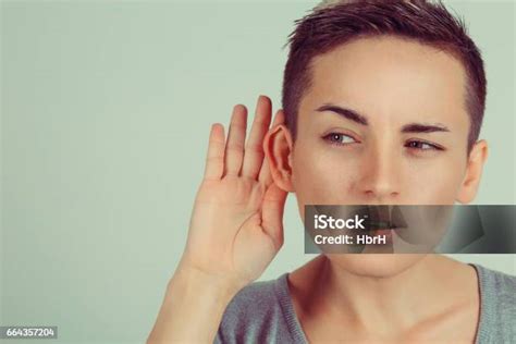 여 자가 가까이 귀 및 수신 회색 벽 바탕에 신중 하 게 고립 된 그녀의 손을 보유 하고있다 인간의 감정이 신체 언어 얼굴 얼굴