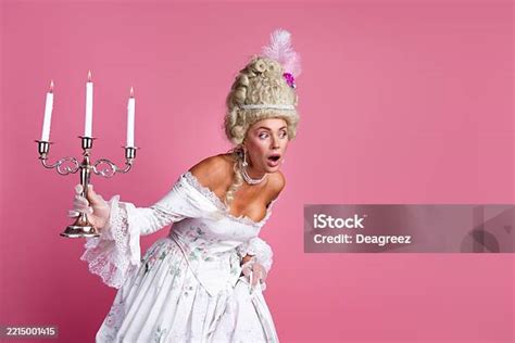 바로크에서 영감을 받은 귀족 여성이 분홍색 배경에 촛대를 들고 있는 기발한 묘사는 빈티지한 매력과 유머를 구현합니다 40 44세에 대한 스톡 사진 및 기타 이미지 Istock