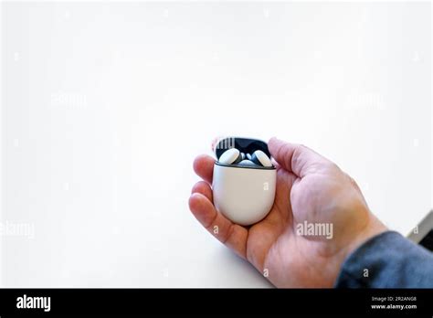 Wireless Earbuds Headphones In Their Charging Case With The Lid Open Being Held By A Caucasian