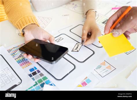 Designers Collaborating On UX UI Mobile App Wireframes And Prototypes With Color Swatches And