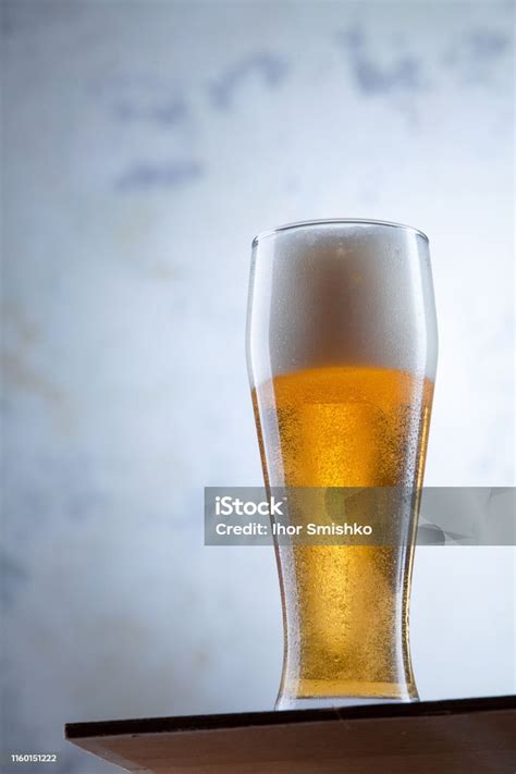 콘크리트 벽 앞에 서 있는 차가운 맥주 잔의 전경을 가까이서 볼 수 있습니다 알코올 차가운 음료 가벼운 맥주 한 잔 광고용 펍 컨셉 포스터입니다 공간을 복사합니다 수직 판매