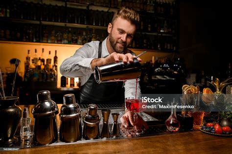 바텐더가 칵테일을 쏟아 붓는 다양한 바 장비와 잔이있는 바 카운터의 매력적인 전망 바텐더에 대한 스톡 사진 및 기타 이미지