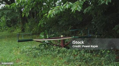 녹슨 금속 회전 목마와 더러운 슬라이드에 시든 나무 좌석이 있는 소름 끼치는 버려진 폐허가 된 놀이터 0명에 대한 스톡 사진 및