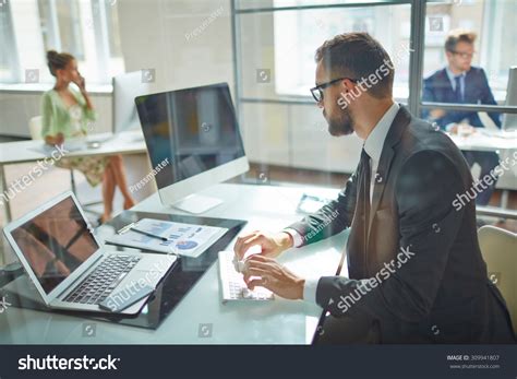Employee Looking At Computer Monitor During Working Day In Office Over 187 Royalty Free