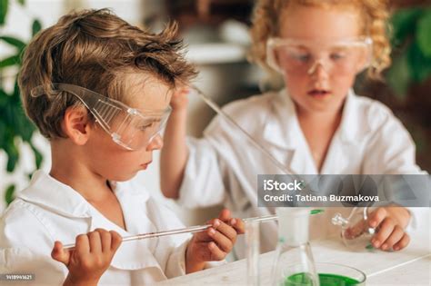 실험실에서 화학 실험을 수행하는 흰색 유니폼을 입은 진지한 어린 소년과 소녀 학교 개념으로 돌아 가기 젊은 과학자 자연과학