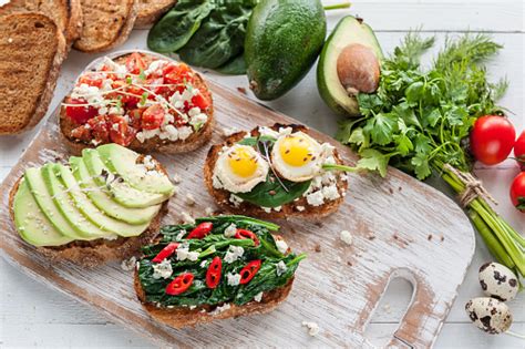 맛있고 맛 있는 브루 쉐 타 토마토 시금치 아보카도 Feta 빨강 칠리 페 퍼와 블루 치즈 마이크로 녹색 참 깨 씨 및 아마 건강 한 먹는 개념 구운 식품에 대한 스톡 사진