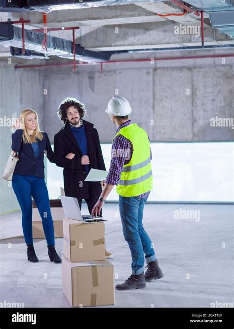 worker using laptop computer while showing house design plans to a