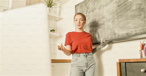 칠판 앞에 서 있는 동안 교사의 질문에 올바르게 대답하는 인공 사지를 가진 창의적인 여성 칠판에 그림을 그리면서 무언가를 시연하는 소녀 원격 교육 개념 사진