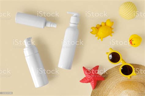 중립 배경에 선 스크린 로션 튜브 태양 보호와 어린이 선글라스와 베이지 색 테이블에 샌드 박스 장난감의 플라스틱 병 어린이 피부 관리 개념 어린이를위한 자외선 차단제 아기