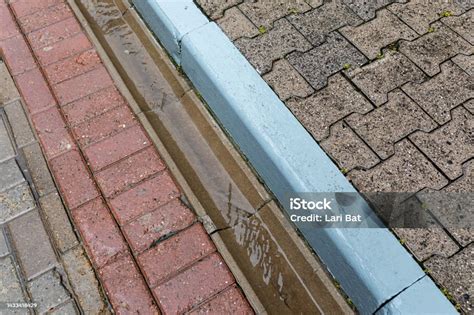 비가 오는 동안 빗물 유출 보도와 도로 사이의 빗물 배수를위한 콘크리트 거터 0명에 대한 스톡 사진 및 기타 이미지 0명