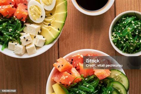 쌀 아보카도 연어 망고 오이 華 샐러드 원시 유기 찌를 그릇에 메 추 라 기 계란 달콤한 양파 간장 소스와 나무 배경 평면도에 華 샐러드 두 접시 클로즈업 0명에 대한 스톡