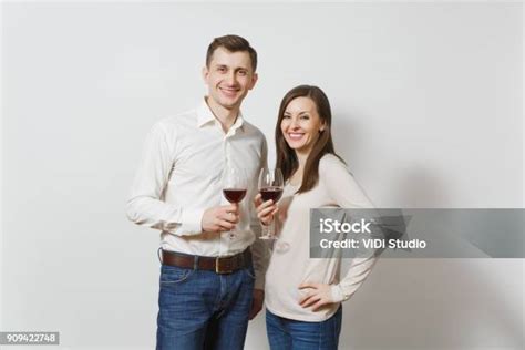 젊은 백인 커플 행복 한 남자와 여자 캐주얼 빛 옷에 사랑에 웃 고 붉은 안경에서 마시는 토스트 만드는 청바지에 고립 된 흰색 배경 와인 광고에 대 한 공간을 복사 합니다