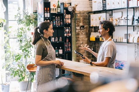 커피 로스터리 주인 두 명이 가게 한가운데에 서서 아무렇지도 않게 담소를 나누고 있고 한 명은 디지털 태블릿을 들고 있다 2명에