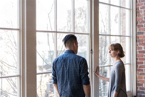 Young Man And Woman Stand At Window In Renovated Old Office Spac By Stocksy Contributor