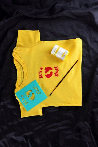 수 제 그림을 가진 아 이들의 T셔츠 봉 어두운 배경에 노란색 패브릭입니다 조정의 과정입니다 사진과 함께 티셔츠입니다 검은색에 노란색 티셔츠 T 셔츠에 대한 스톡 사진 및