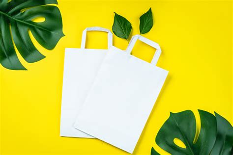 노란색 배경에 환경 친화적 인 종이 봉지 노란색 배경에 녹색 잎이있는 재활용 종이 쇼핑백 폐기물 제로 플라스틱 없는 개념 환경 보호 지속 가능한 생활 가방에 대한 스톡 사진