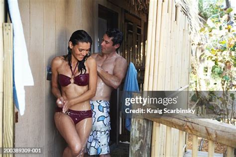 Couple In Swimsuits Rinsing Off In Outdoor Shower Smiling High Res