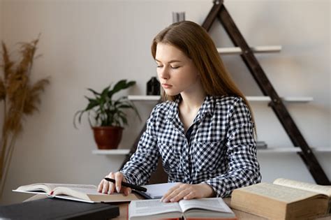 피곤한 백인 소녀 학생 컨설턴트 또는 교사는 백과 사전 참조 서적의 여러 책을 읽고 자료를 공부하여 강의를 준비합니다 온라인 교육 또는 원격 학습 경영학 석사에 대한 스톡