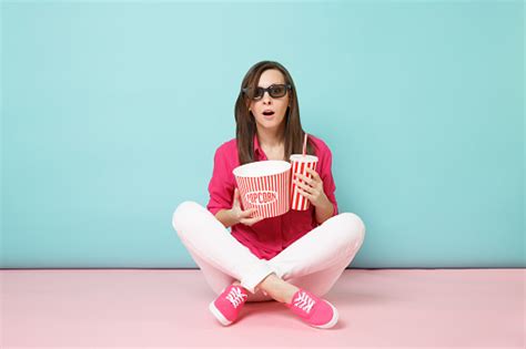 전체 길이 세로 재미 여자 장미 셔츠에서 흰색 바지 밝은 핑크 블루 파스텔 벽 배경 스튜디오에 고립 된 보고 영화 필름을 바닥에 앉아 패션 라이프 스타일 개념입니다 복사