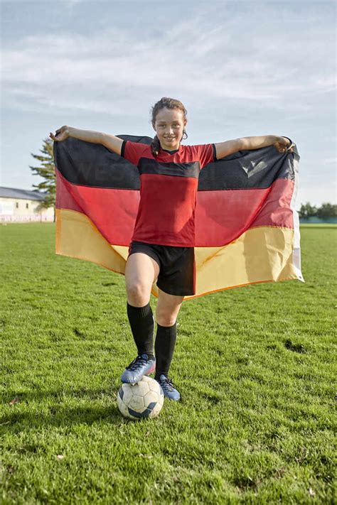 Happy Girl Standing With Soccer Ball And Holding German Flag On Field