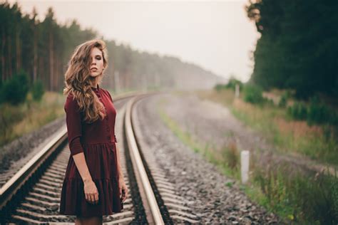 곱슬 자연 머리를 가진 아름 다운 소녀 철도에 숲에서 자연을 즐길 수 있습니다 철도에 부르고뉴 드레스를 걸어 꿈꾸는 레이디 새벽에 레일에 영감을 여자의 여성 초상화입니다