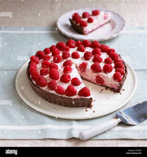 Double Chocolate Raspberry Tart With Single Slice Cut Away Seen On Plate In Background Stock