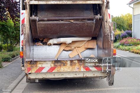 주거 지역의 아스팔트 도로에 쓰레기 컨테이너 쓰레기 트럭 공동 부피가 큰 폐기물에 대한 혼합 폐기물의 분쇄를위한 분쇄기로 재료 폐기물 가구를 운반 쓰레기차에 대한 스톡 사진