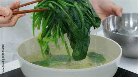 뜨거운 물에 삶은 시금치를 건져서 참기름과 마늘 맛간장을 넣고 버무려 완성하는 시금치 나물 Vídeo De Stock Adobe Stock