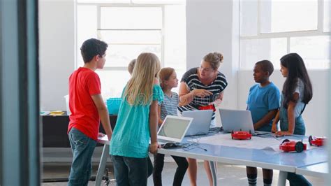 Group Of Students With Female Teacher In School Computer Coding Class