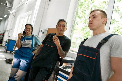 직장에서 재미 제복을 입은 다양한 역학 팀 두 남자와 여자가 말하고 웃고 샌드위치를 먹고 자동차 수리 점에서 휴식을 취하면서 웃음에 대한 스톡 사진 및 기타 이미지 Istock