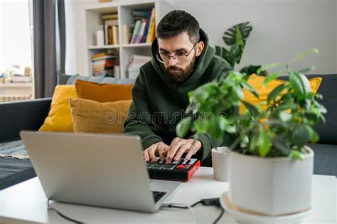 Man Recording Electronic Music Track With Portable Midi Keyboard On Laptop Computer In Home