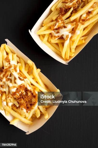 검은 배경의 종이 상자에 치즈 소스와 양파를 곁들인 감자 튀김 상단 보기 평면 누워 오버 헤드 위에서 클로즈업 0명에 대한 스톡