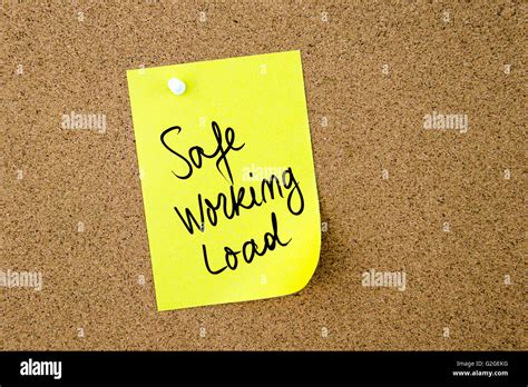 Safe Working Load Written On Yellow Paper Note Pinned On Cork Board With White Thumbtack Copy