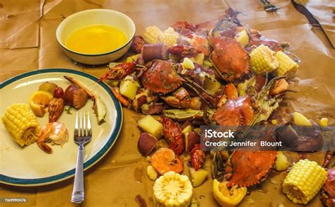 옥수수 감자 양파 레몬 탄수화물 새우새우와 매운 종기로 소시지를 포함한 녹은 버터 한 그릇과 함께 갈색 종이에 제공되는 전통적인 케이준 해산물 종기 케이준 음식에 대한 스톡