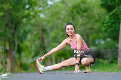 초상화 건강한 라이프 스타일 개념으로 도시 자연 공원에서 야외에서 조깅 운동을하기 전에 스트레칭을하는 야외 복장의 쾌활한 아시아 여성 주자 45 49세에 대한 스톡 사진 및