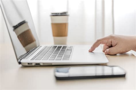 노트북과 스마트폰이 있는 창가 책상에서 재택근무를 하는 여성과 커피를 마시는 여성 Brand Name Smart Phone에 대한 스톡 사진 및 기타 이미지 Brand