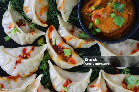 찐 모모 닭고기와 혼합 야채로 채워진 흰 밀가루와 물 반죽 칠리 오일이 뿌려진 오렌지 매운 디핑 소스의 라메킨을 둘러싼 접시에 올려진 모습 높은 전망 0명에 대한 스톡 사진