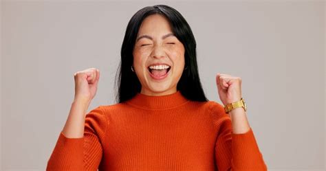 아시아 여성 스튜디오에서 주먹과 축하 배경에 따라 보너스 목표 및 상품에 흥분하고 행복합니다 소녀 사람 우승자는 와우와 함께 환호 성공과 함께 선물을 위해 눈을 감고 미소를